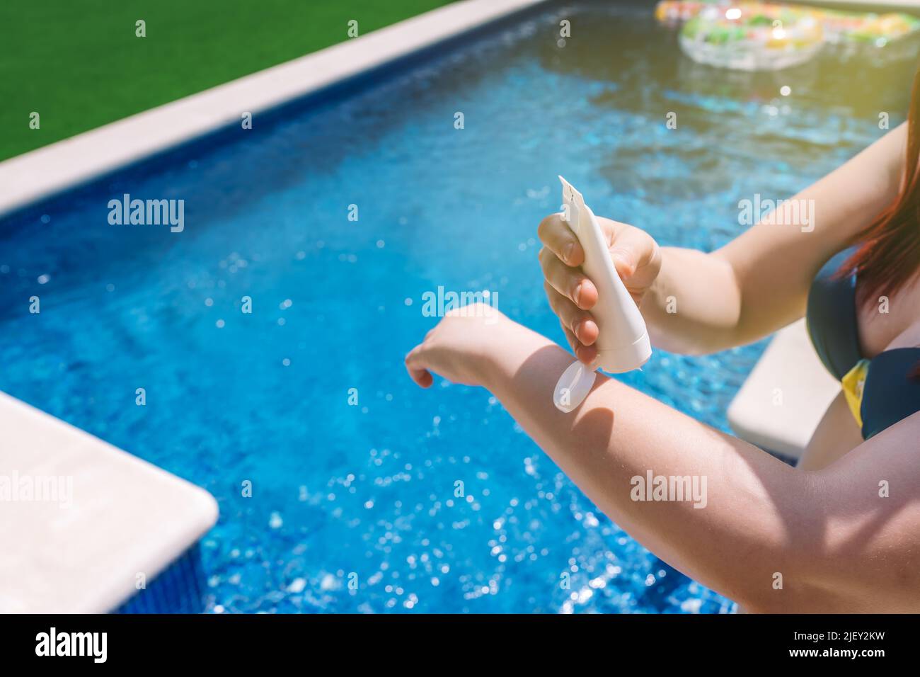 unrecognizable young woman applying sunscreen to the skin on her arms ...