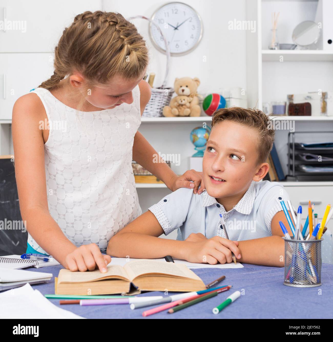 Girl is explaining to boy how to solve homework Stock Photo - Alamy