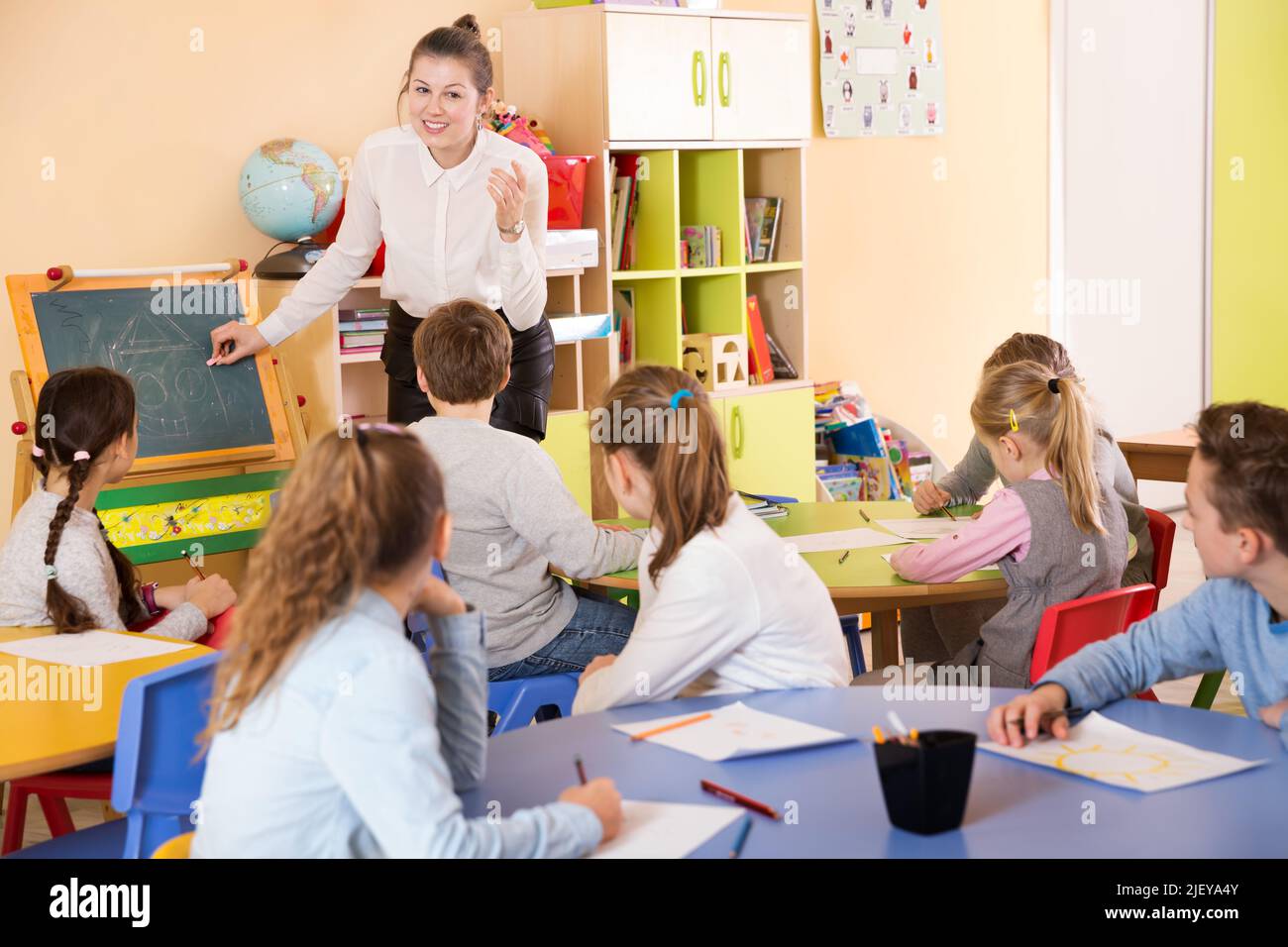 Teacher standing at blackboard in classroom Stock Photo - Alamy