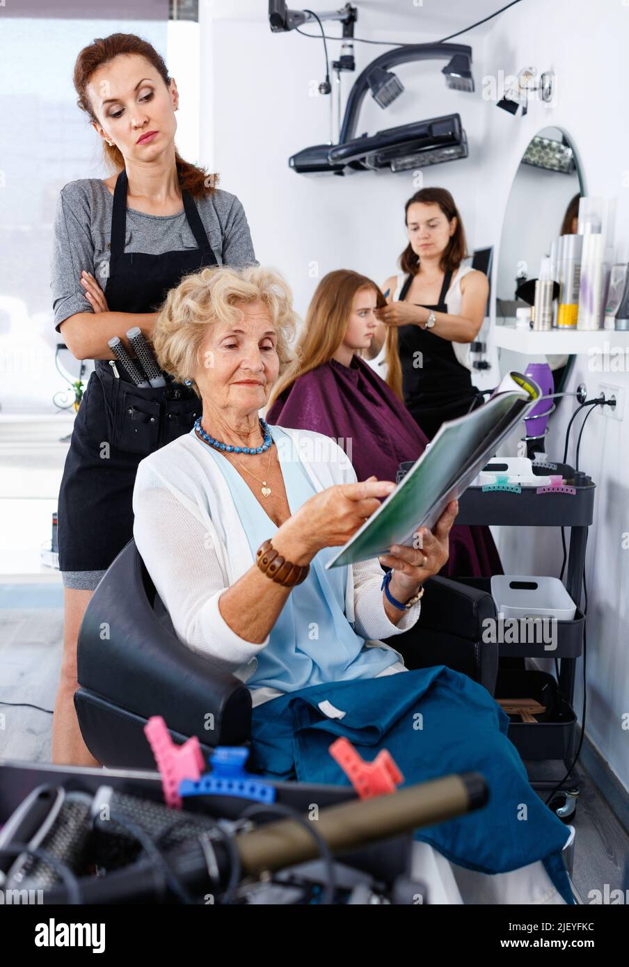Young woman hairdresser in hair salon helping to senior woman ch Stock ...