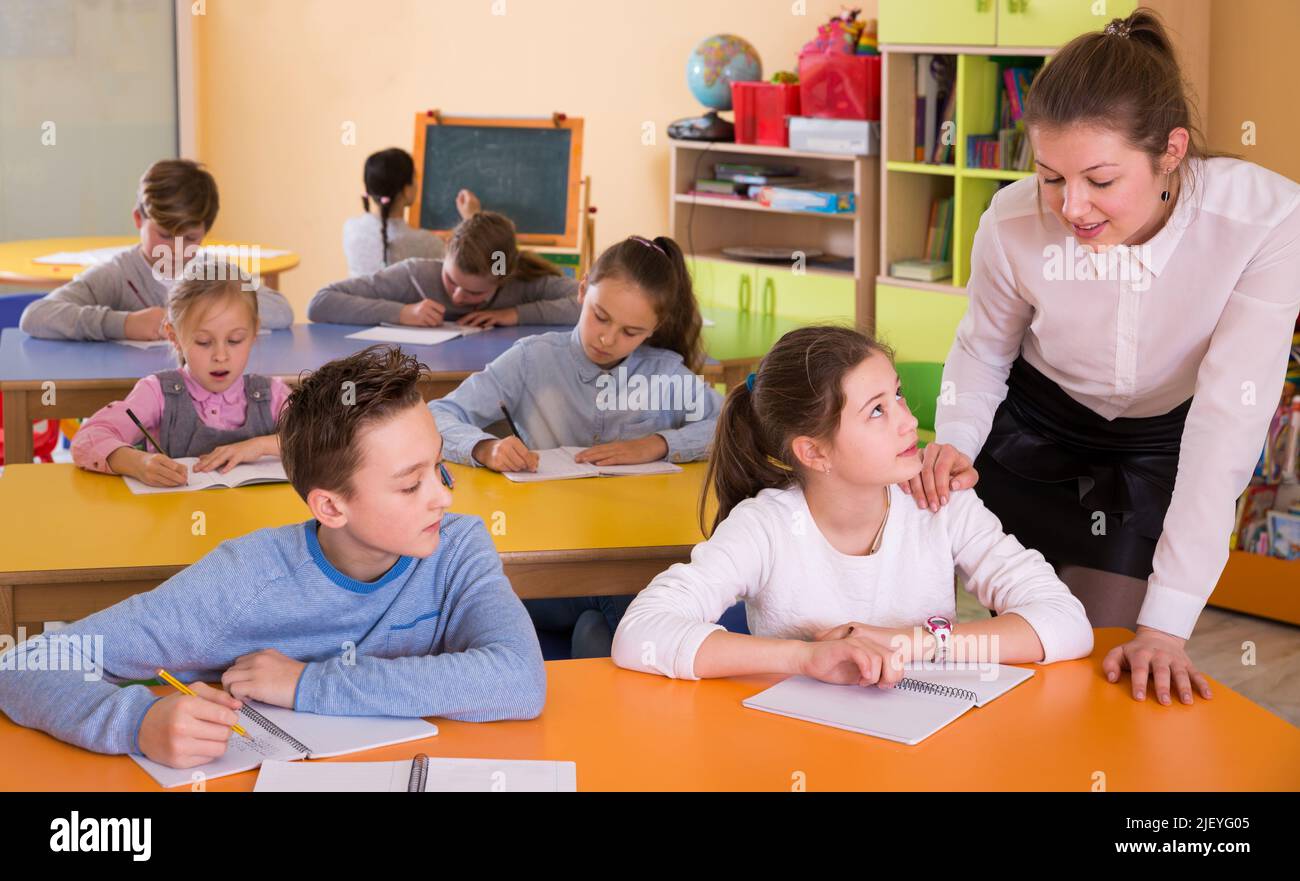Adult teacher helping to elementary age children Stock Photo - Alamy