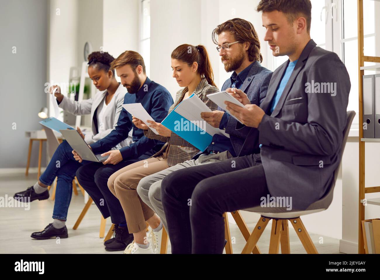 Multiracial group of people sitting in office and waiting for their job ...