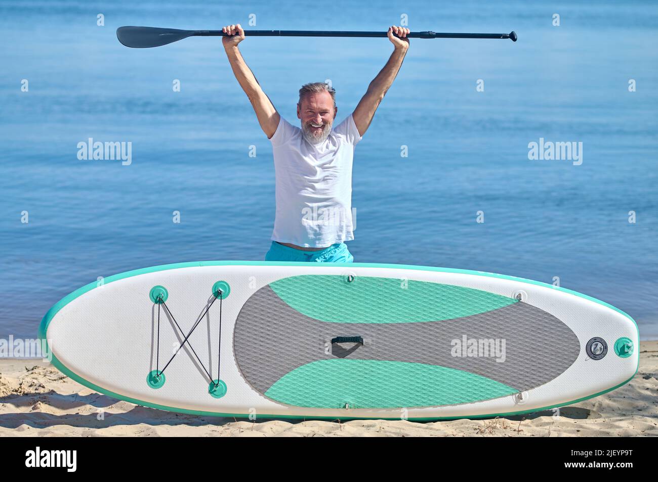 Man with raised paddle standing behind rowing board Stock Photo - Alamy
