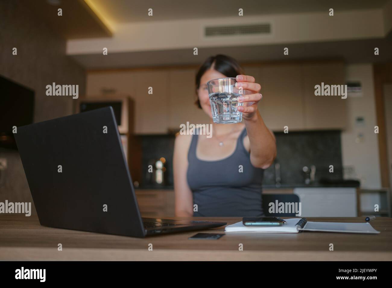 Shot of beautiful asian woman working with laptop while drinking glass ...