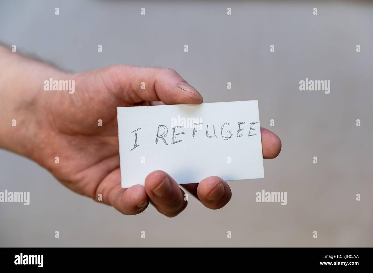 I refugee. Words written in jagged letters. A man's hand holds a white ...