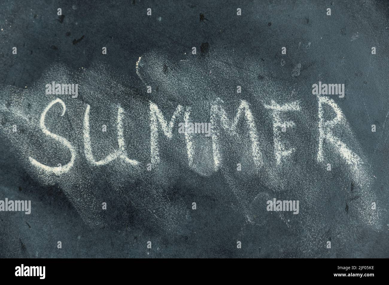 Semi-erased word SUMMER on black chalkboard. Handwritten word. Fuzzy ...