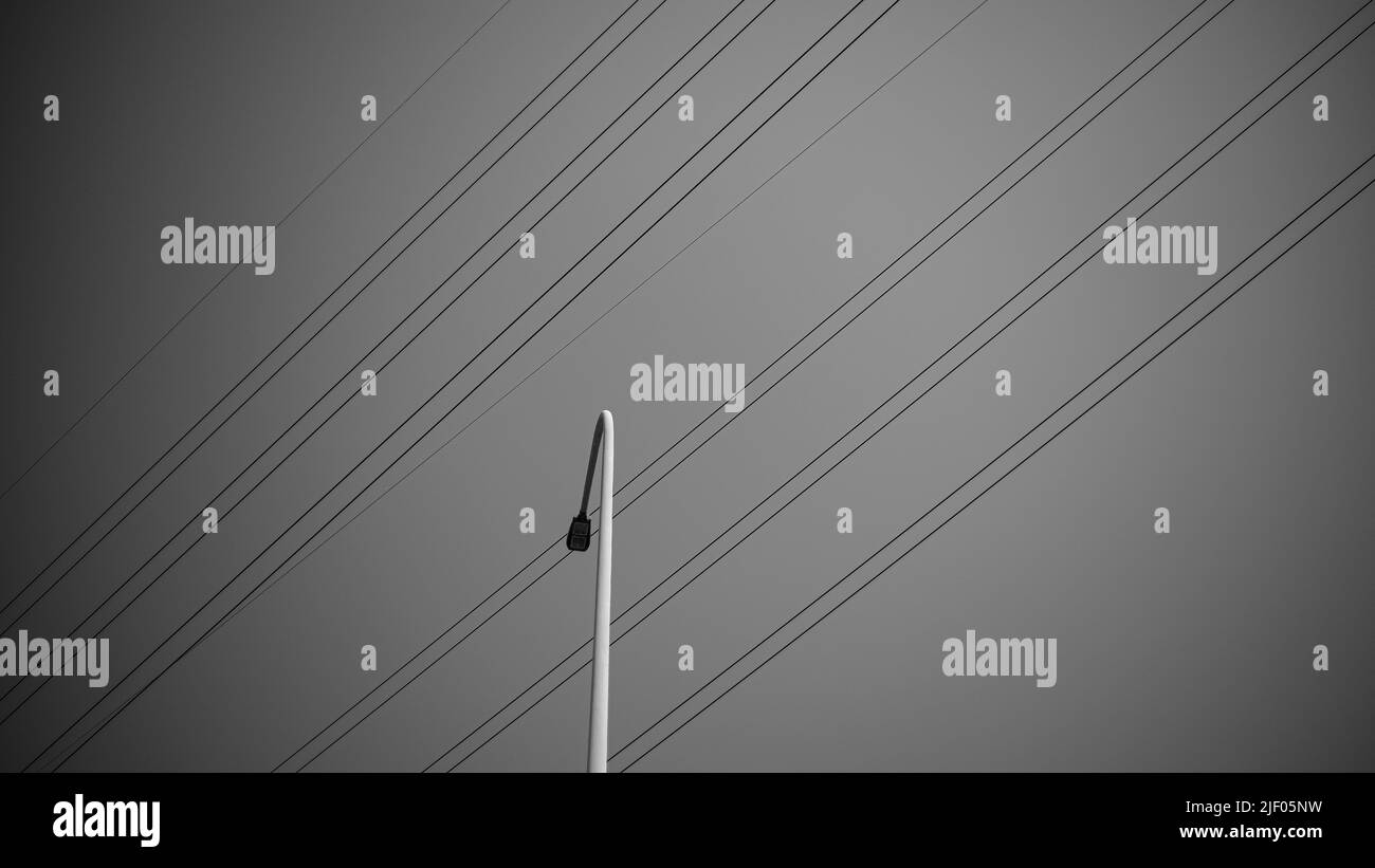 A monochrome of a streetlight with electric wires on the background ...