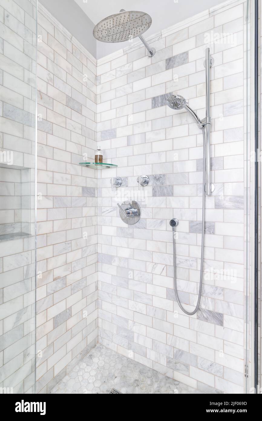 A remodeled shower with marble subway tiles on the walls, hexagon floor ...