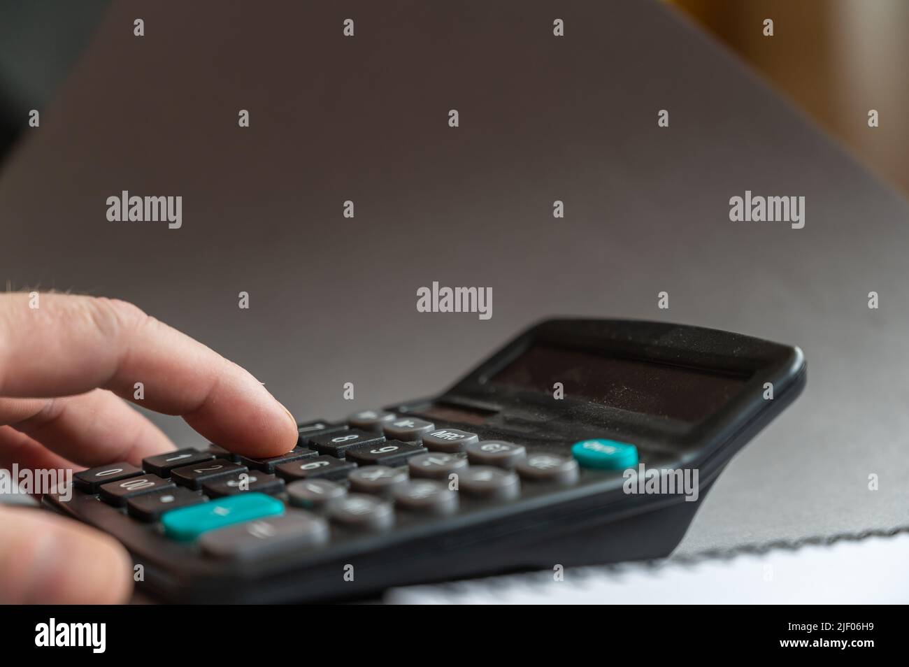 Close-up of a man's hand doing calculations on a calculator. Index ...
