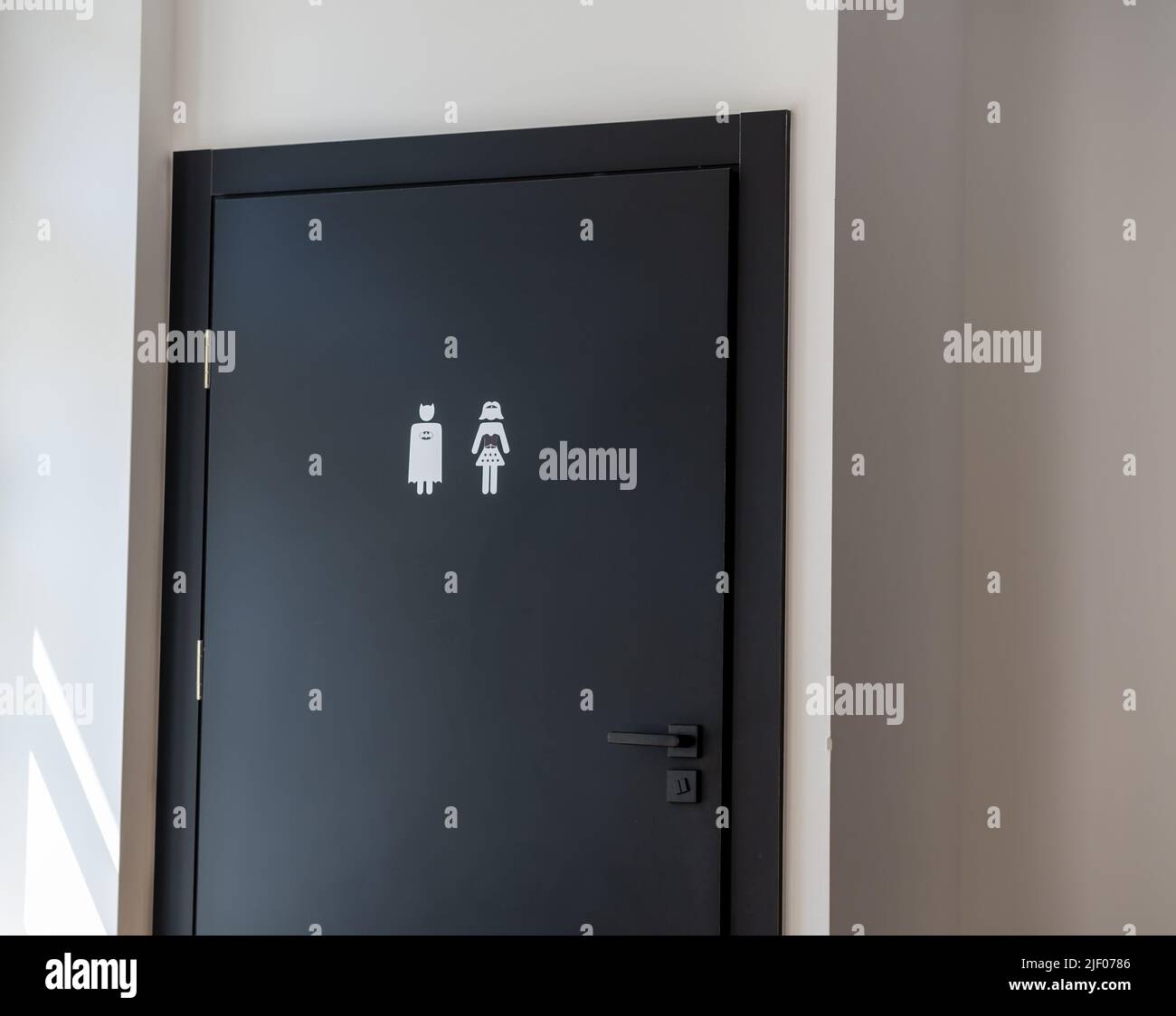 A black restroom toilet door with a Batman and woman symbols Stock ...