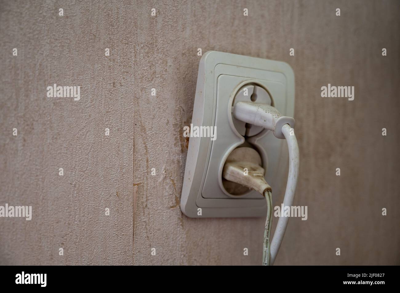 Broken electrical outlet in beige wall. White electrical outlet with ...