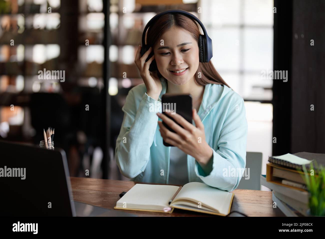 Happy asian student girl in wireless headphones using learning app on ...