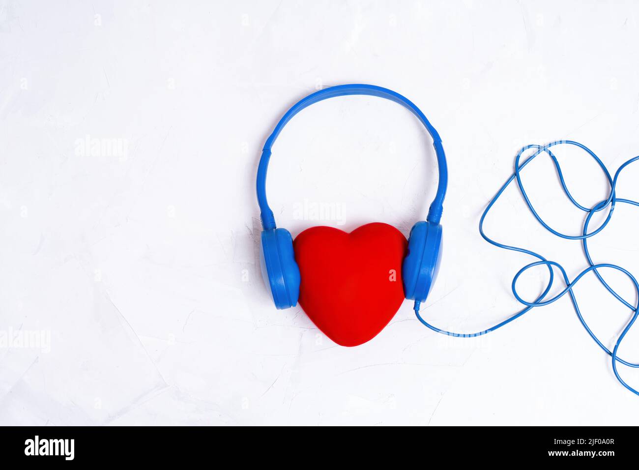 Wired headphones over a large red heart shape isolated on a neutral ...