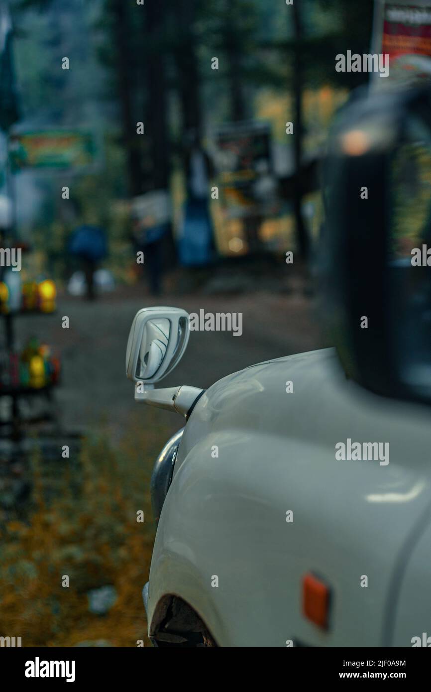 A vertical shot of an outer rear-view mirror of a vintage car in the ...