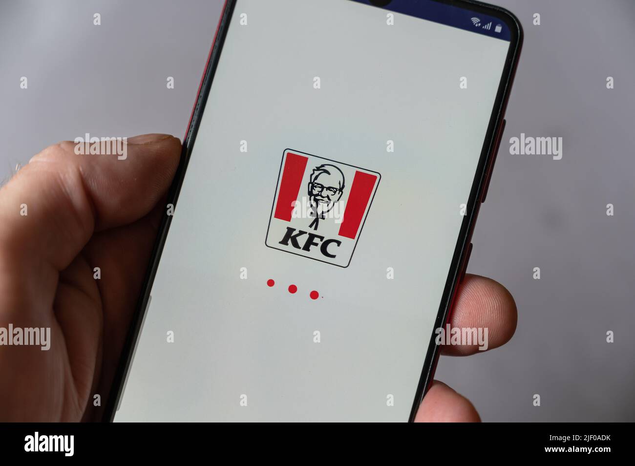 Male hand holding smartphone with KFC logo on screen. Kentucky Fried ...