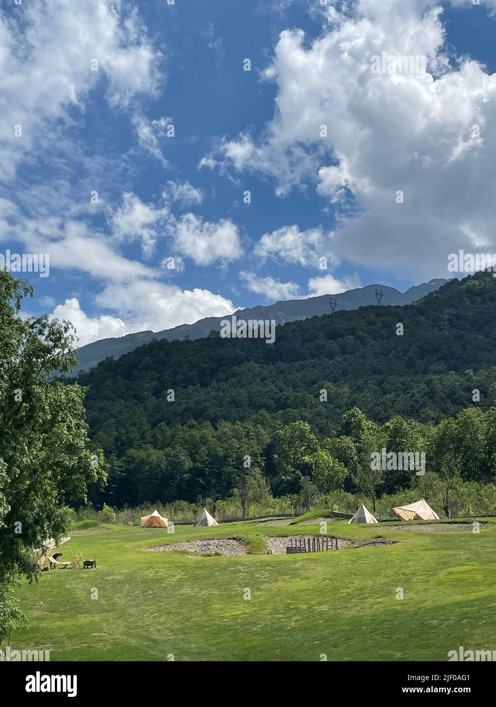 A Vertical view of a summer camp with tents and mountains in the ...