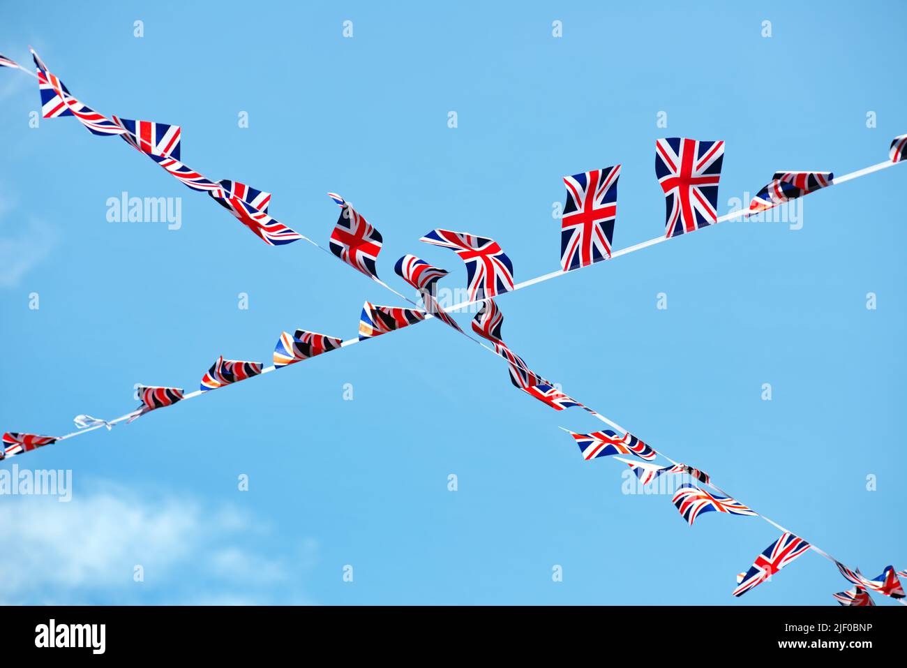 A low angle of the Great Britain flag bunting crossing on blue sky ...