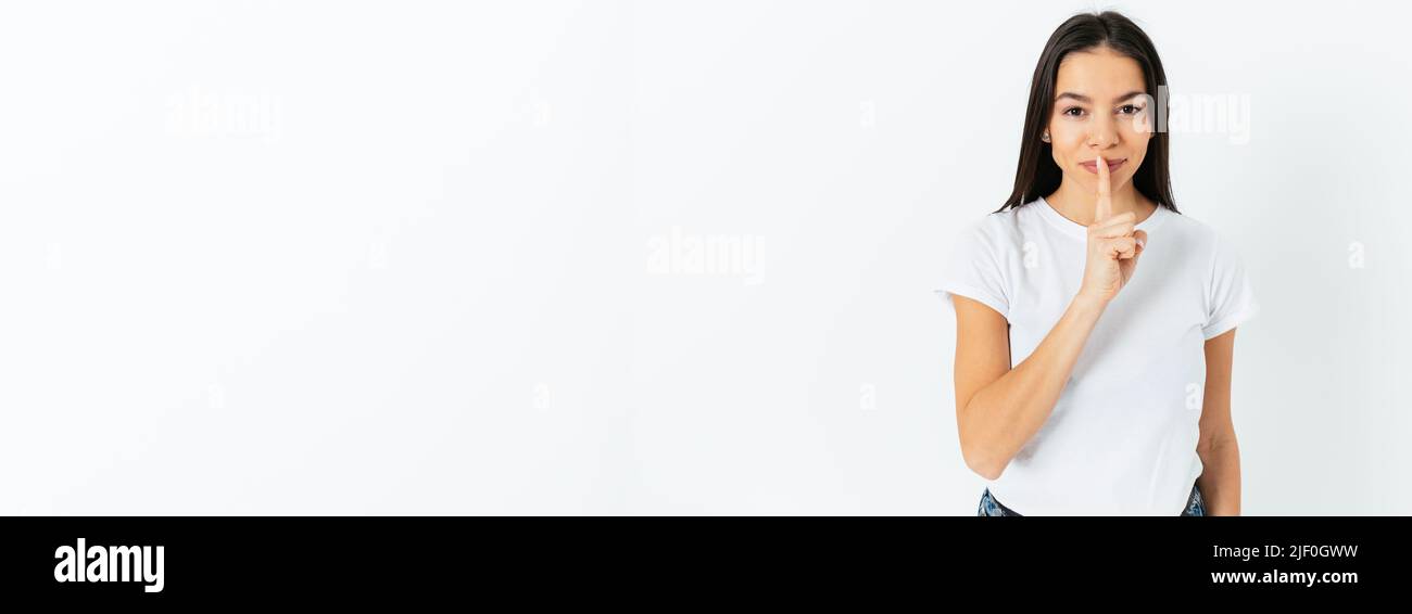 Young woman showing shh keep the secret sign with finger to lips ...