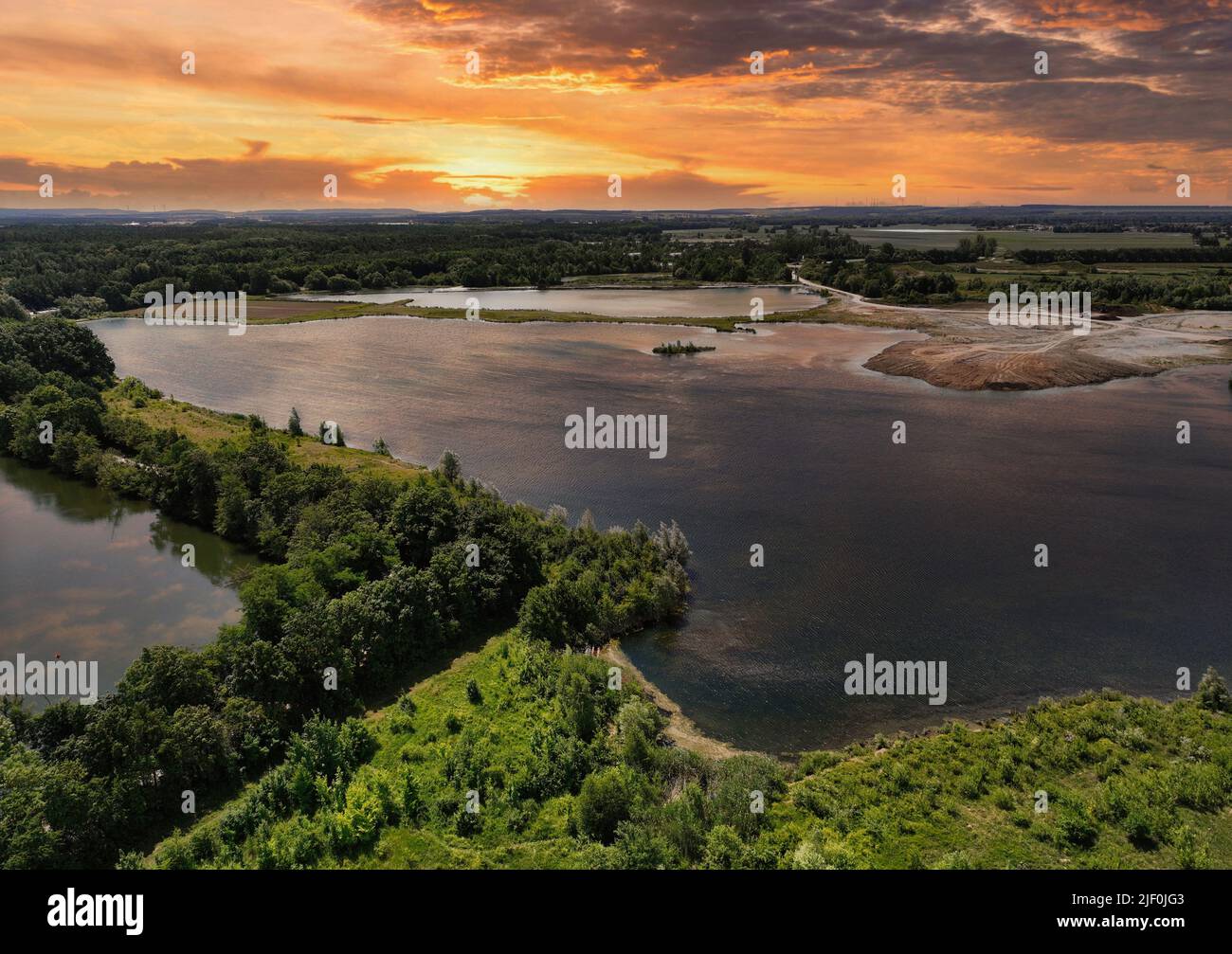 A beautiful view of a calm lake surrounded by trees at scenic sunset ...