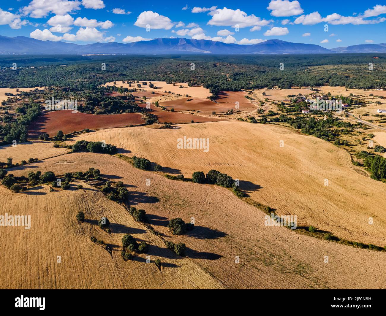 Aerial view of arable fields with blue sky and mountains in the ...