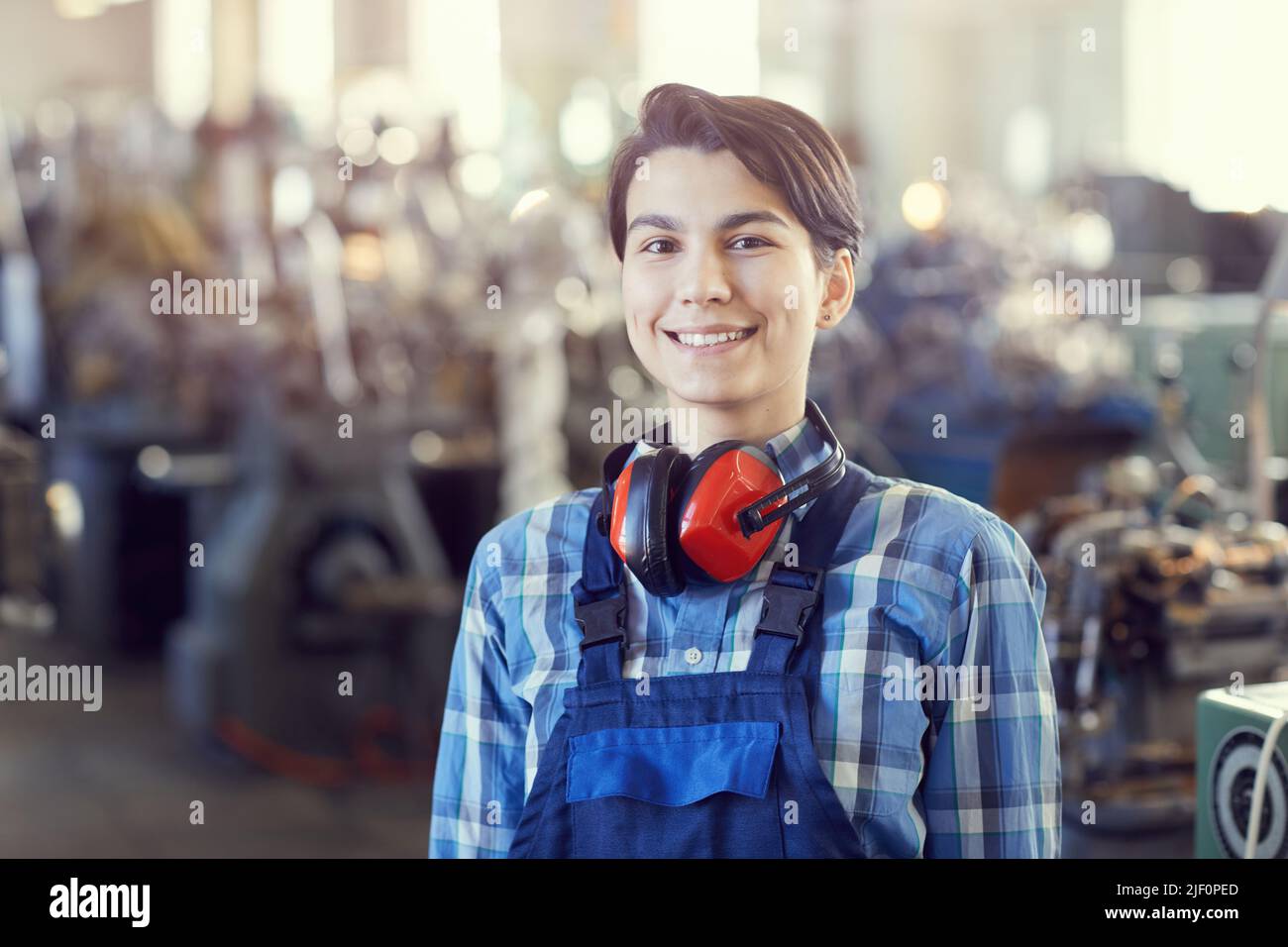 Portrait of cheerful satisfied brunette female factory worker with ...