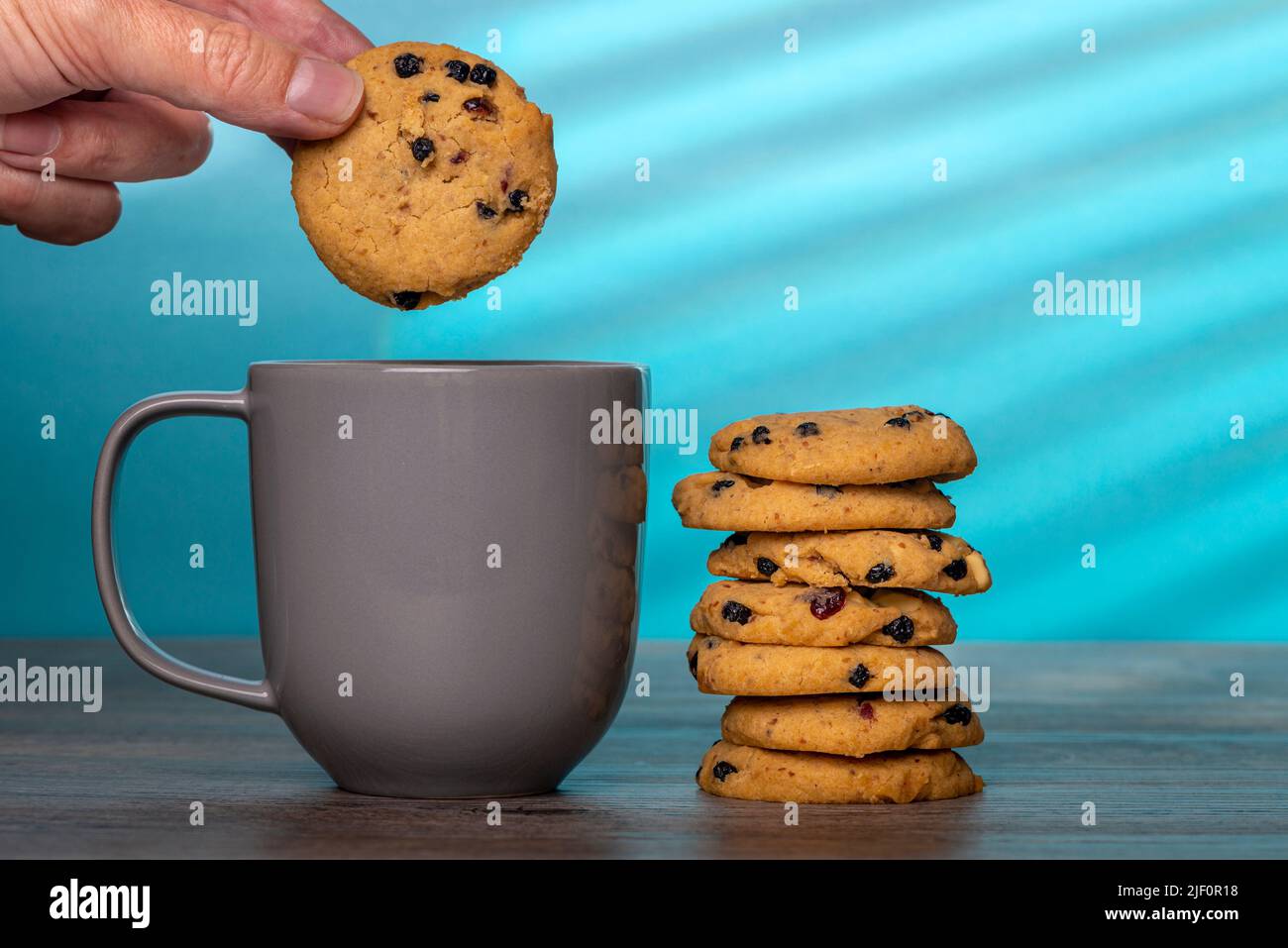 stack of home cooked cookies and a grey mug against a blue background ...