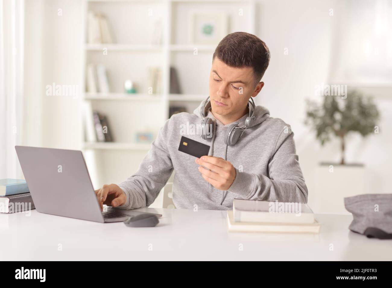 Guy using a credit card and a laptop computer at home Stock Photo - Alamy