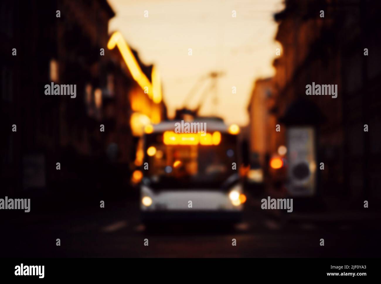 A blurry image of a trolleybus driving down the street of a night ...