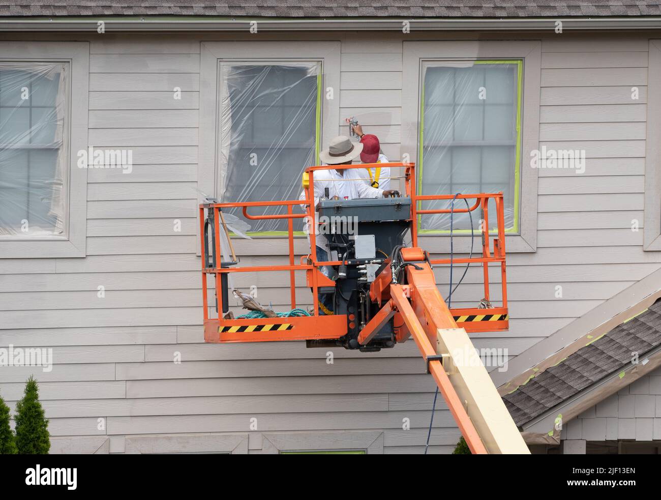Two home painters in articulating boom lift spray painting townhouse ...