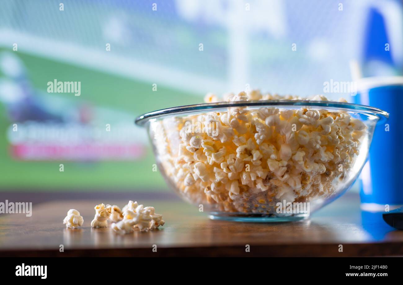 Stadium, football field on the big screen TV. A large bowl of popcorn ...
