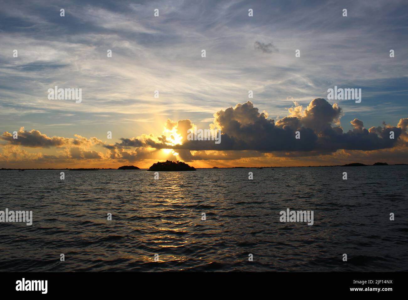 colourful sun rising over the dark blue sea with clouds and rays of ...