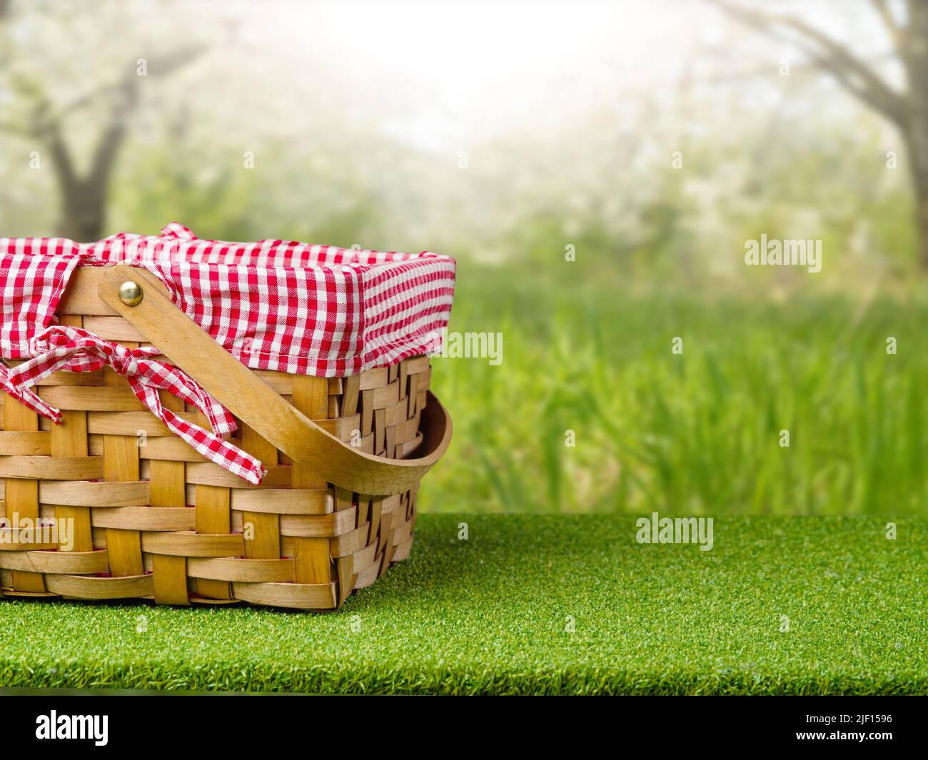 On the bright green grass, a beautifully decorated straw picnic basket ...