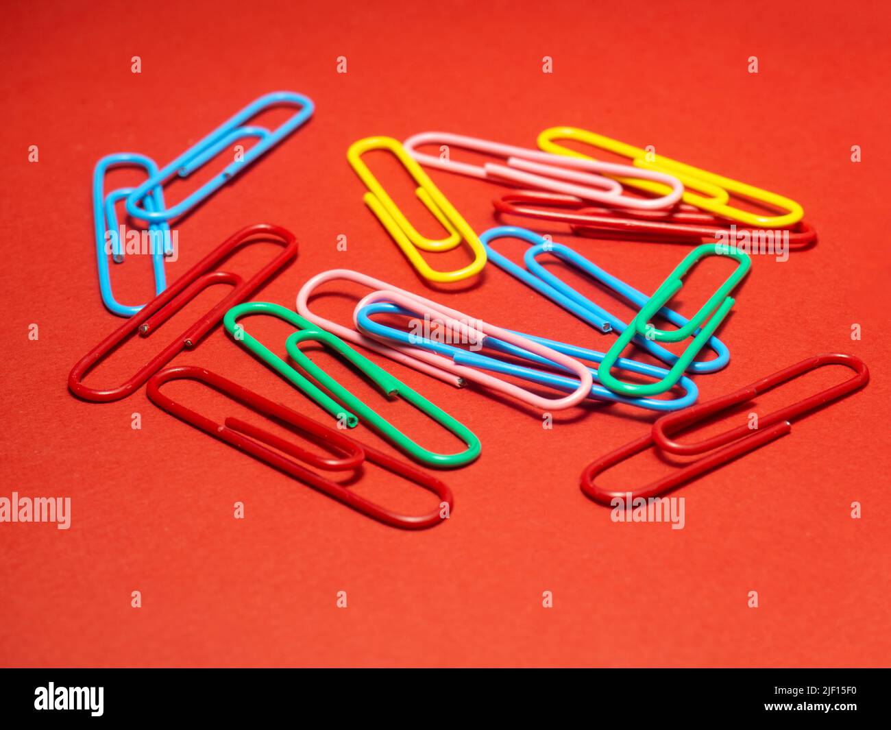 Colored paper clips on paper. Office supplies. Business goods. Colorful ...