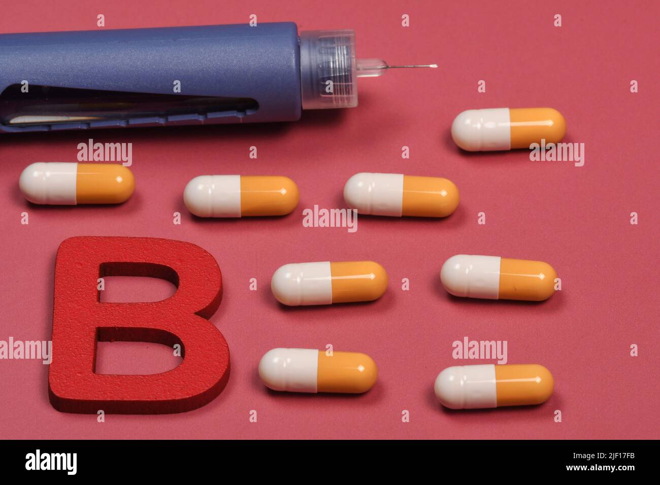 yellow and white medicine capsules on red background and insulin pen ...