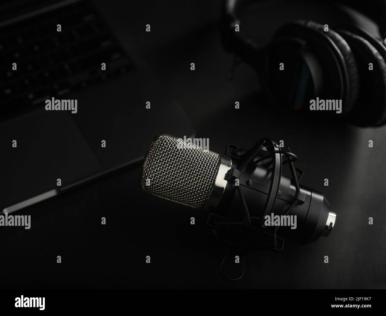 On a black background, a studio microphone and studio headphones. Close ...