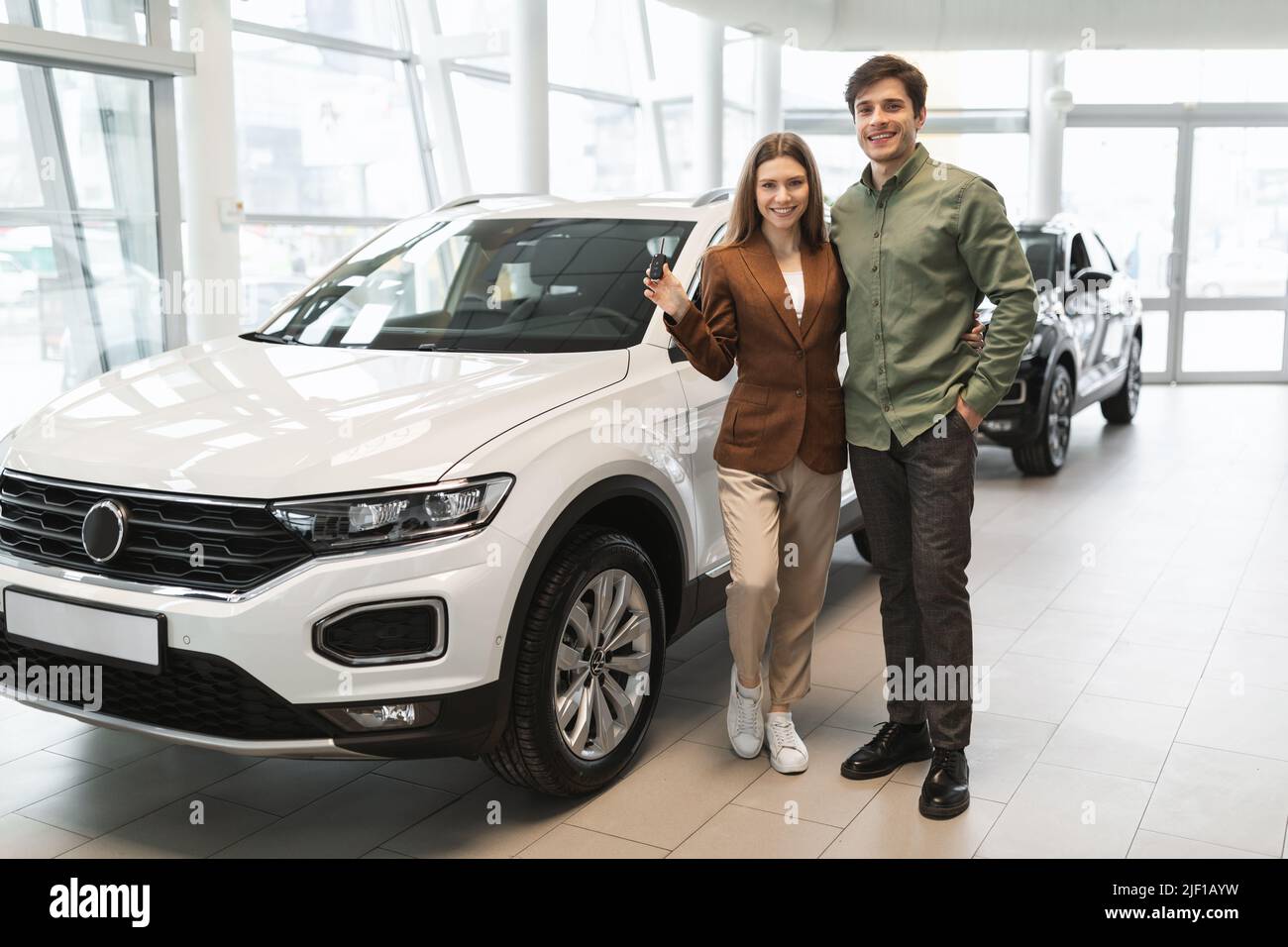 Full length of cheery young couple showing key to their new car at ...