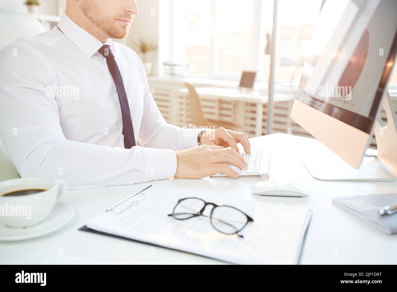 Cropped image of concentrated young businessman in formal shirt sitting ...