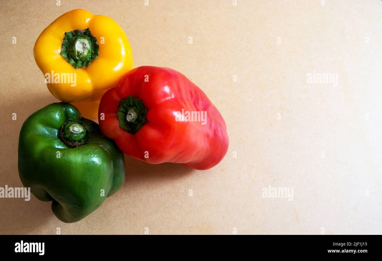 Three peppers of different colors leaning against each other on the ...
