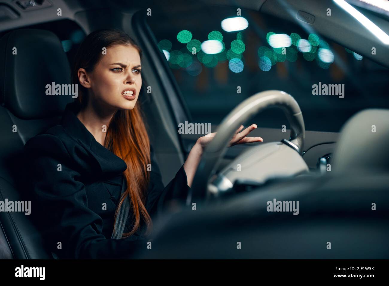 horizontal photo of a woman sitting at the wheel of a car with a tense ...