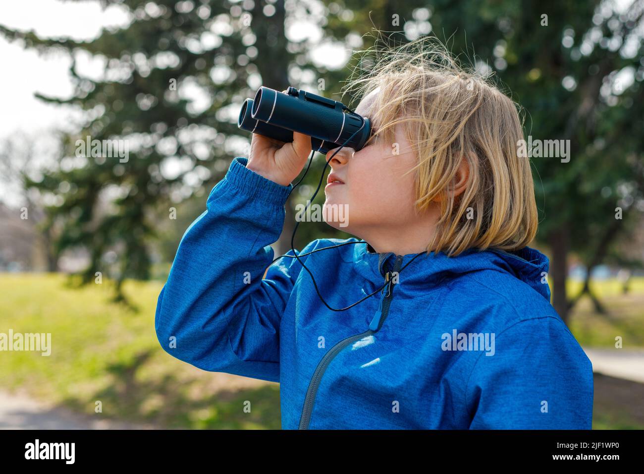 Child looking through binoculars in the park. Portrait of a little boy ...