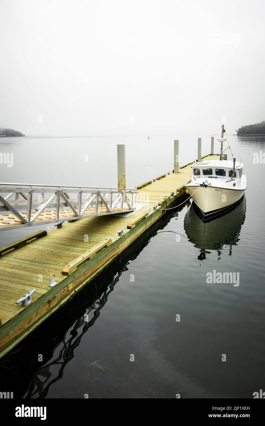 Cape Island-style boat reflecting on calm water while tied up to a ...