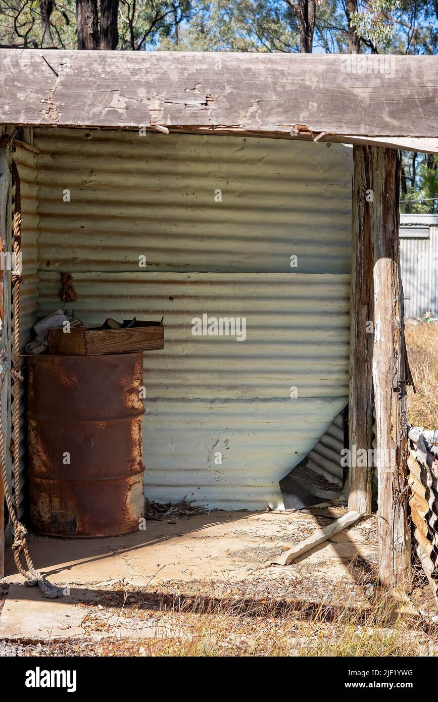 An old open abandoned tin shed sheltering a rusty drum past its use by ...