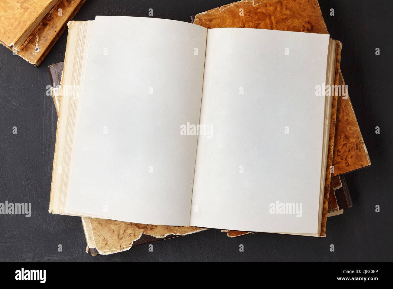 Open vintage book or notebook in a dust jacket on a stack of old shabby ...