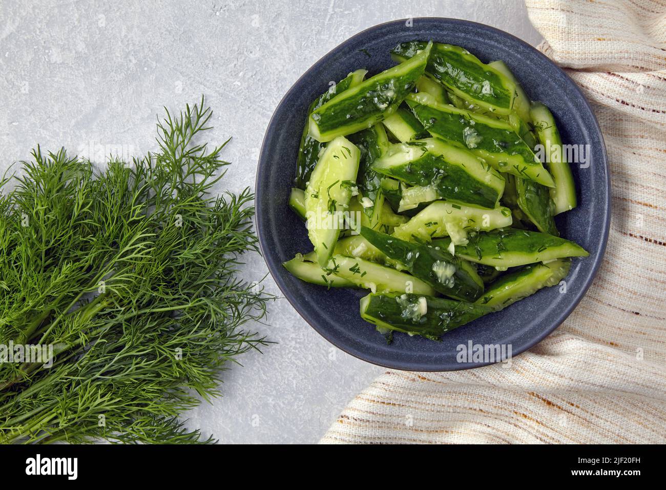 Smashed lightly salted broken cucumbers in a ceramic bowl surrounded by ...