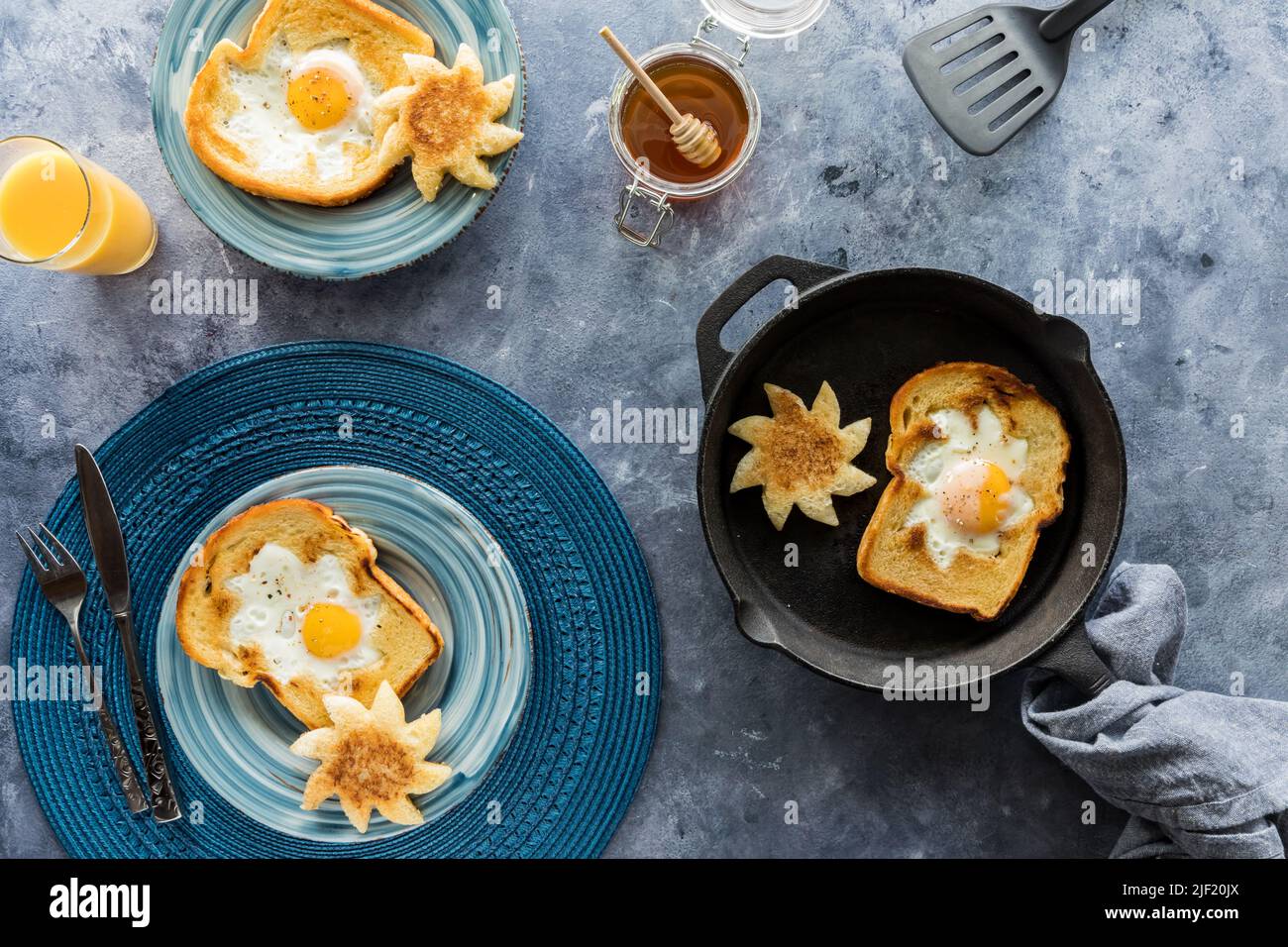 A fry pan with a sunshine fried egg inside a toast with others on ...