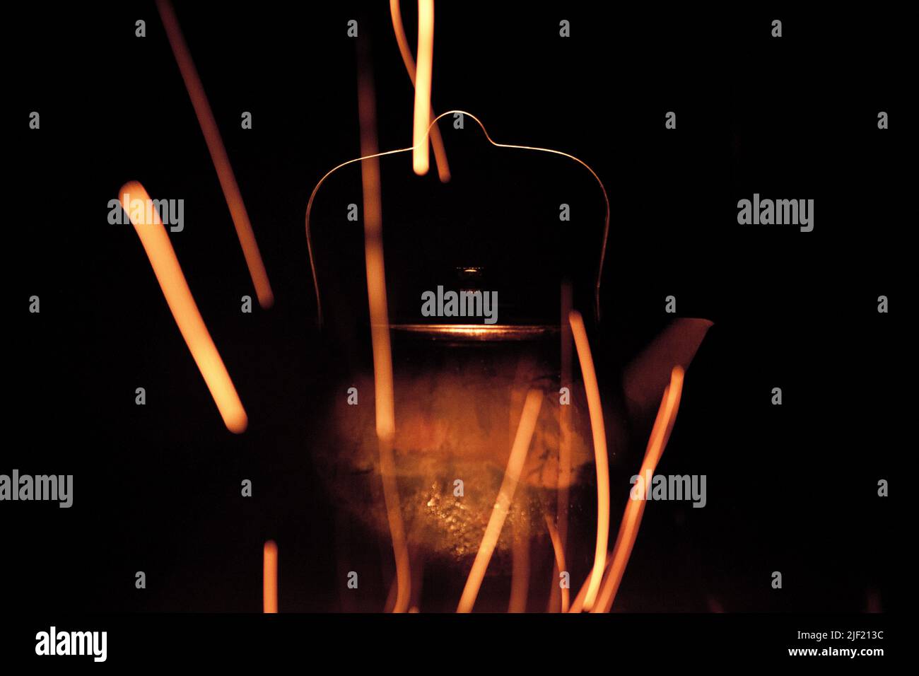 A metal kettle handing near orange fire sparks Stock Photo - Alamy