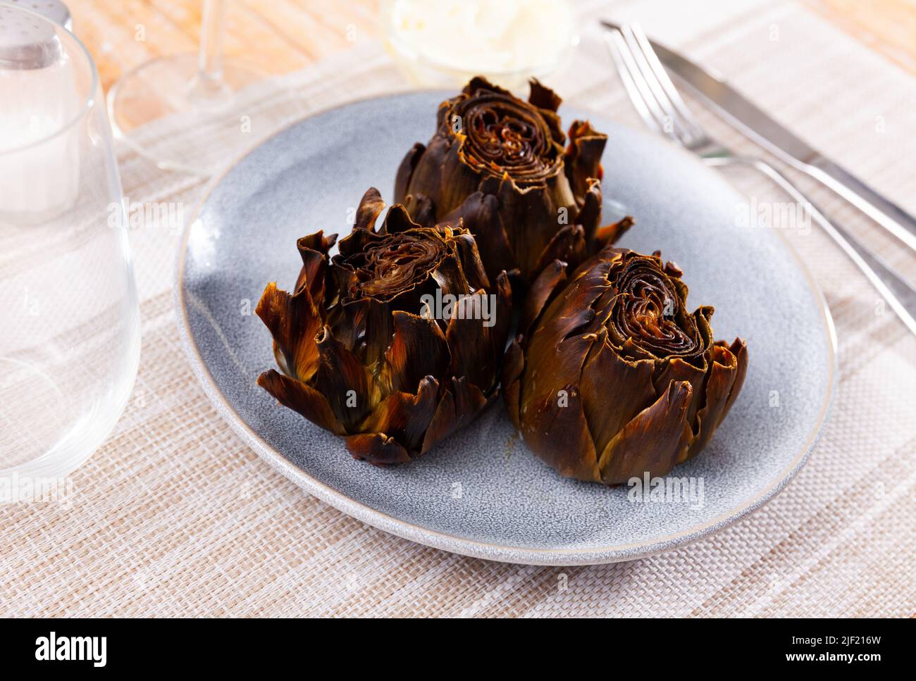 Delicious spicy-tasting roasted whole artichokes served on plate Stock ...