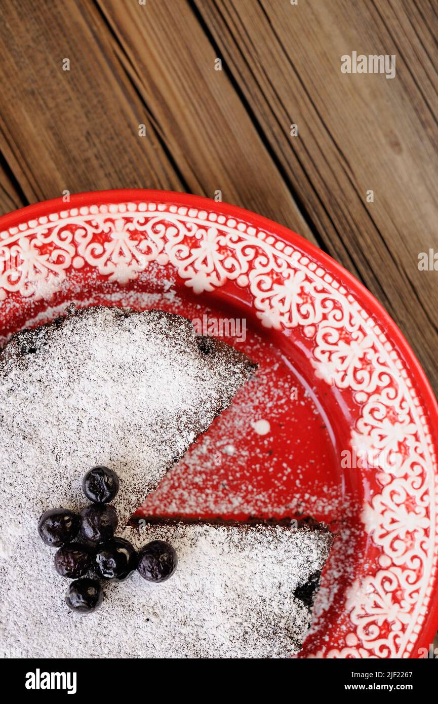 Chocolate pie with blueberry and icing sugar cut in red plate vertical ...