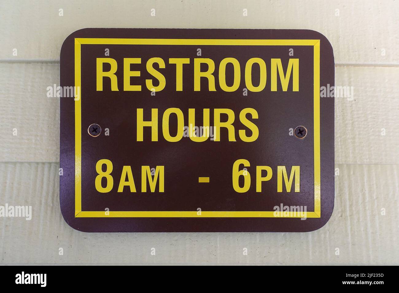Brown sign indicating restroom hours of operation Stock Photo - Alamy