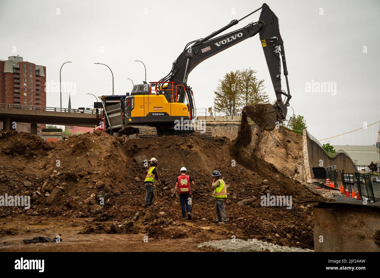 An excavator demolishes a highway ramp and places dirt into a dump ...